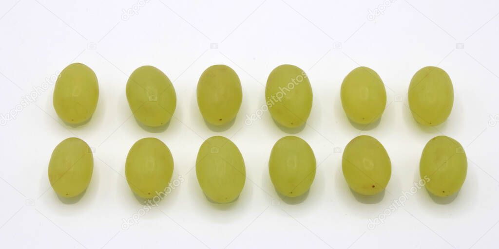 Primer plano de doce uvas alineadas aisladas sobre un fondo blanco 2024