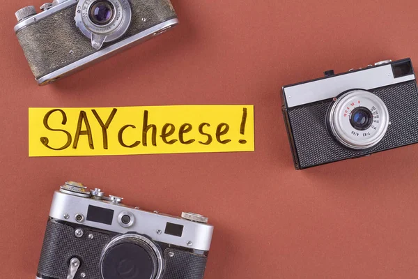Top view three retro photo cameras on red background. Say cheese ...