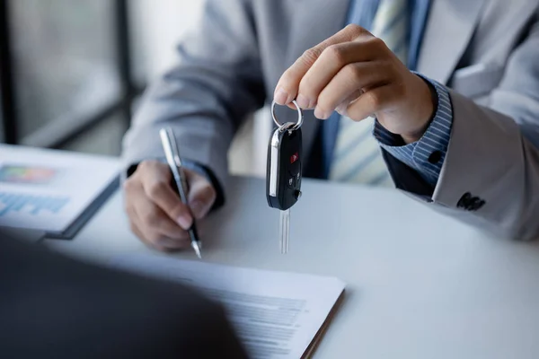 The car salesman hands the key to the customer after discussing the ...