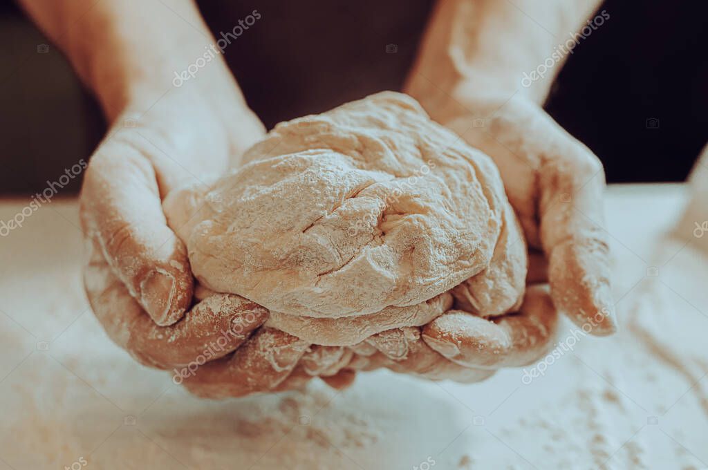 manos de panadero masculino sosteniendo masa amasada espolvoreada con ...