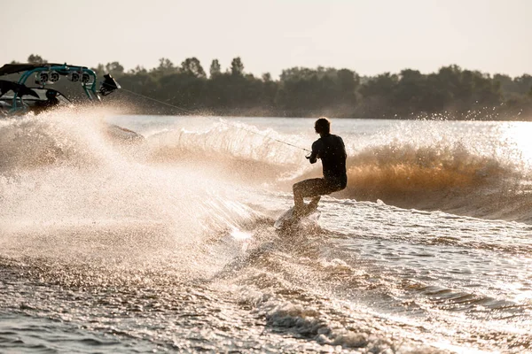 Great view of active man riding wakeboard behind motor boat on ...