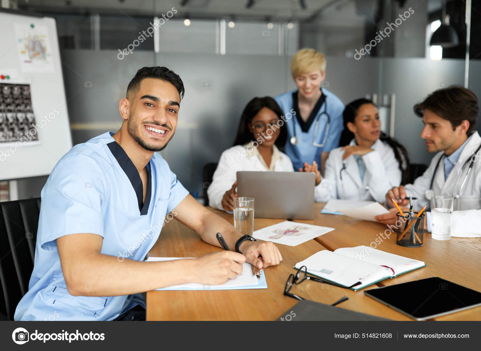 Handsome doc smiling at camera while having brainstorming with colleagues Stock Photo by ©Milkos ...