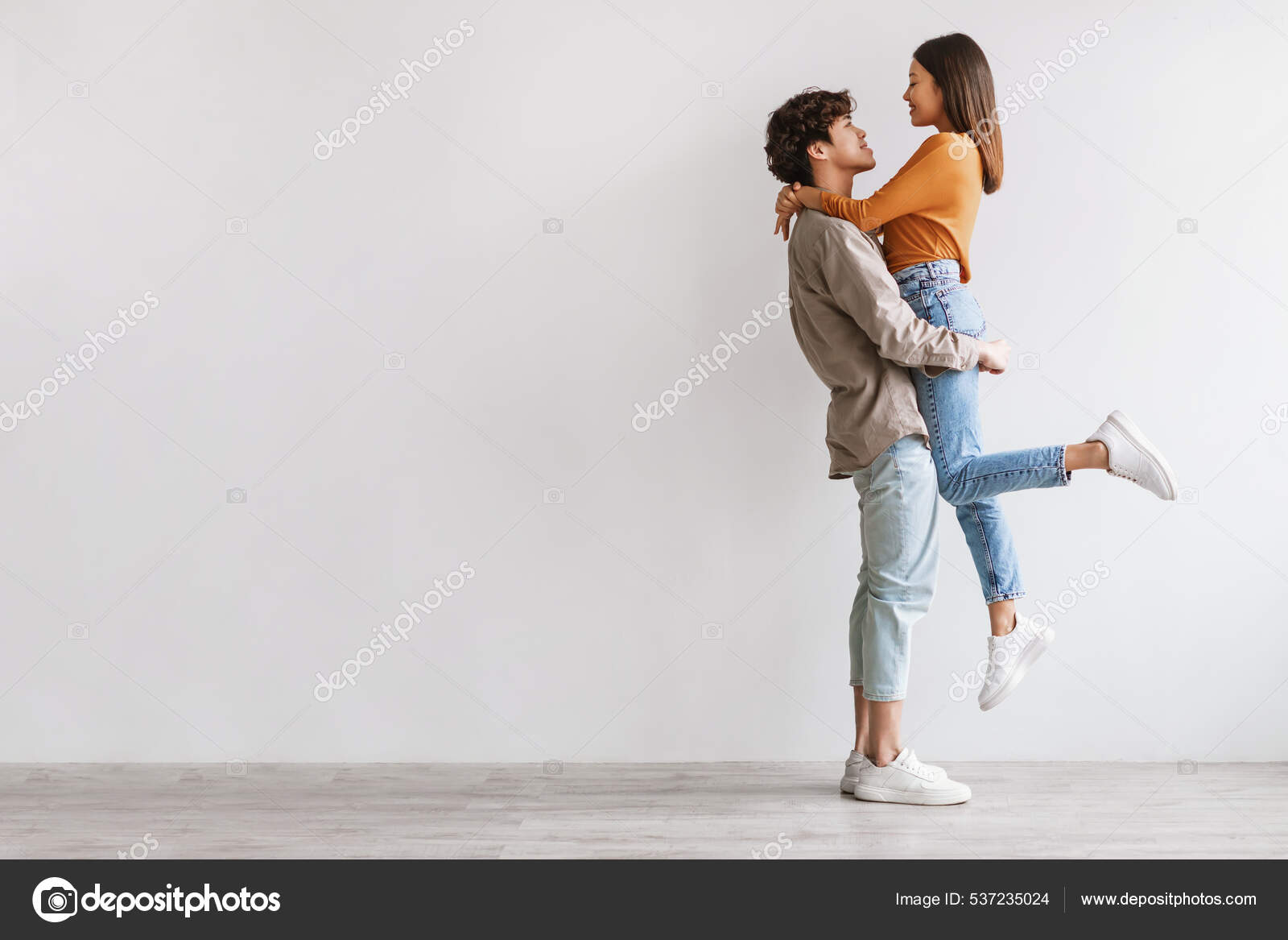 Side view of romantic young Asian guy holding and hugging his beloved ...