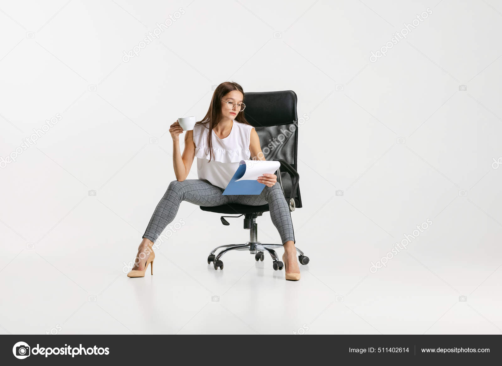 Full-length image of business woman reading report and drinking coffee ...