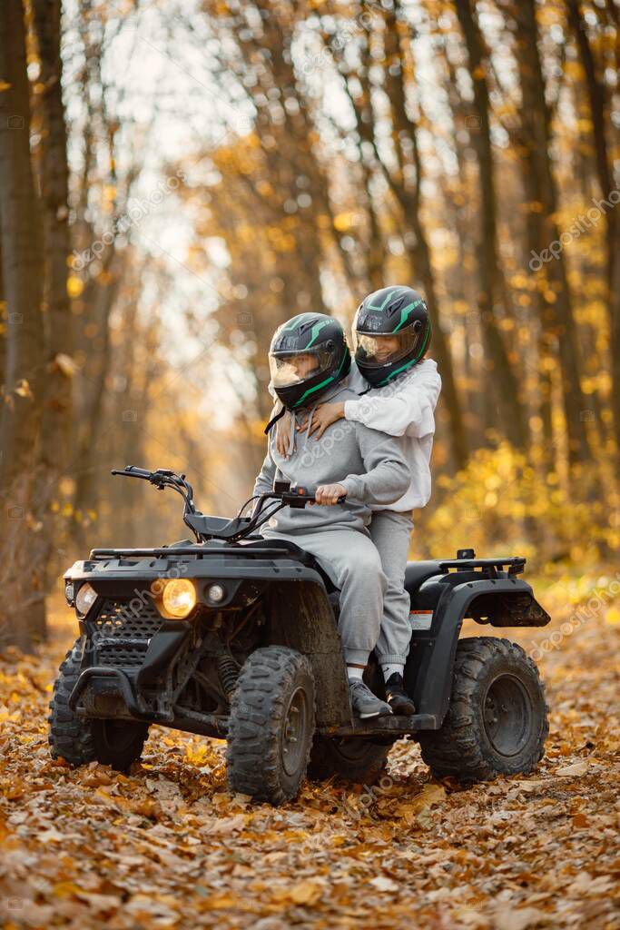 A young caucasian man and woman riding an ATV quad bike in autumn ...