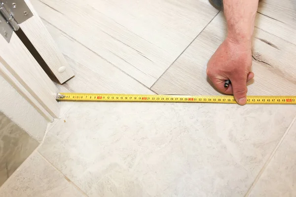 Installation of threshold indoors. Man with a measuring tape ...