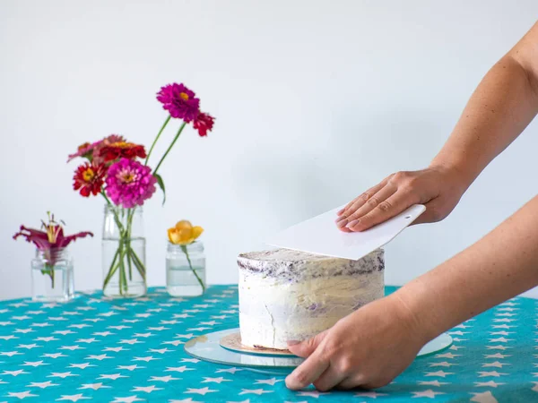 Woman spreading the icing to cover the top of the cake. Home baking ...