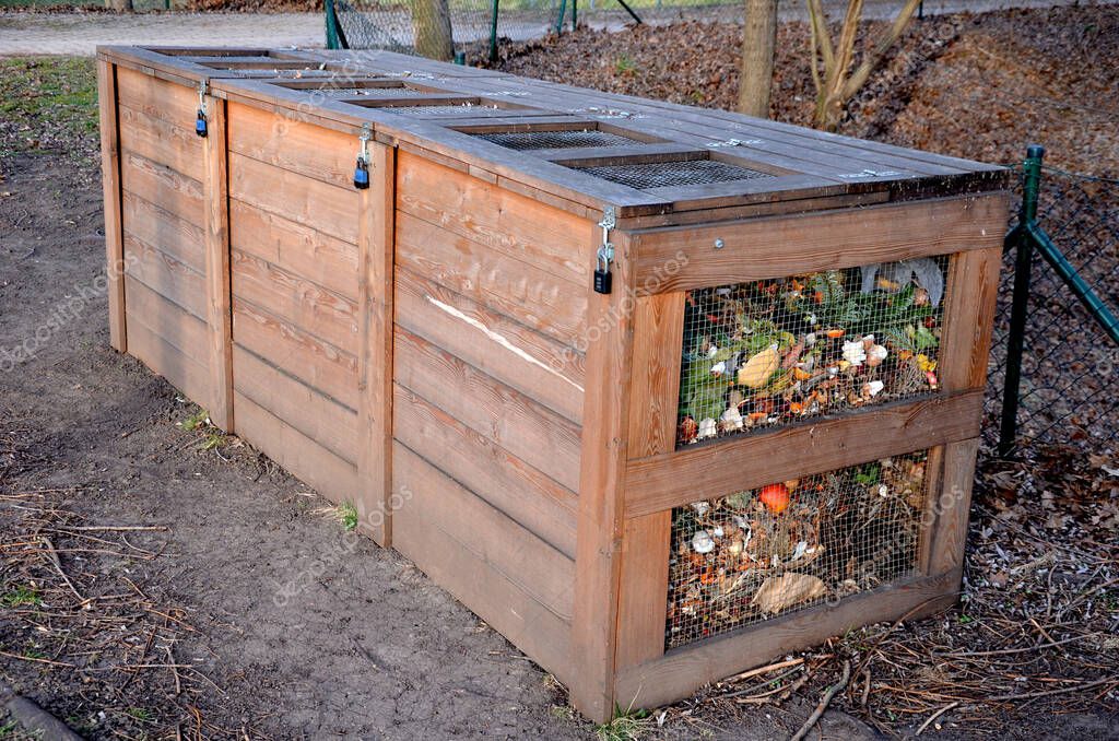 Compostador de madera con malla en los laterales. Dentro hay sobras de ...
