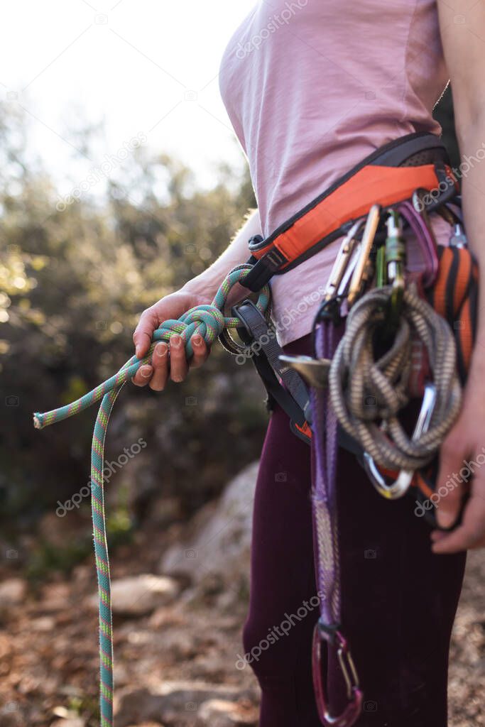 Un escalador prepara equipo para escalar, una mujer sostiene una cuerda ...