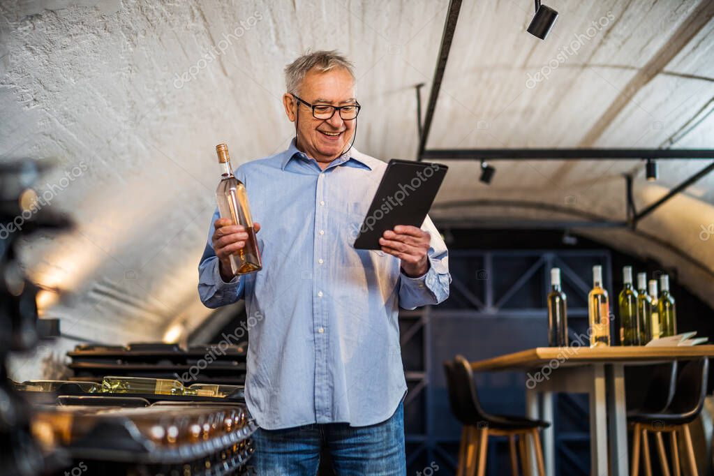 Retrato del hombre mayor que es dueño de la bodega. Está examinando la ...