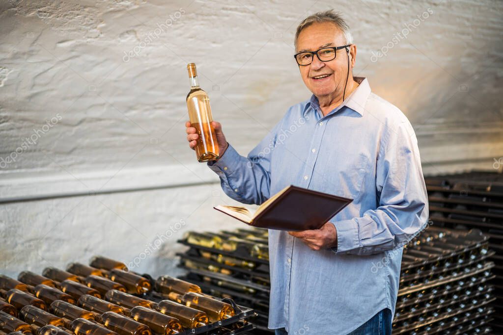 Retrato del hombre mayor que es dueño de la bodega. Está examinando la ...