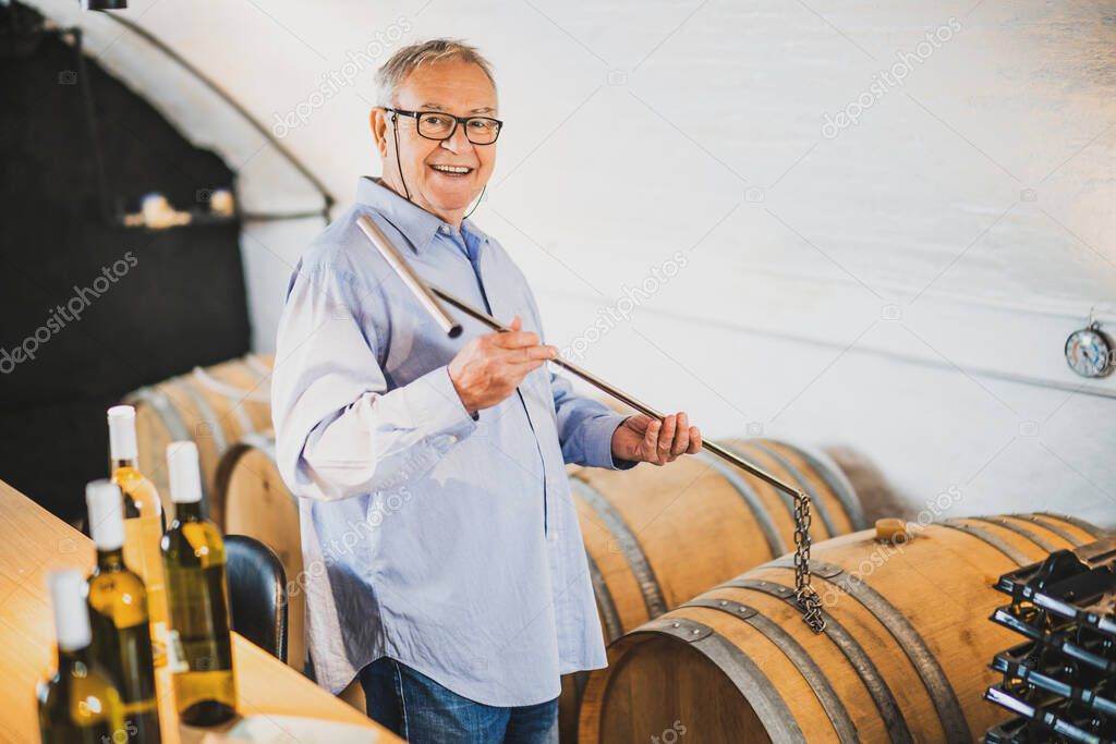 Retrato del hombre mayor que es dueño de la bodega. Está examinando la ...