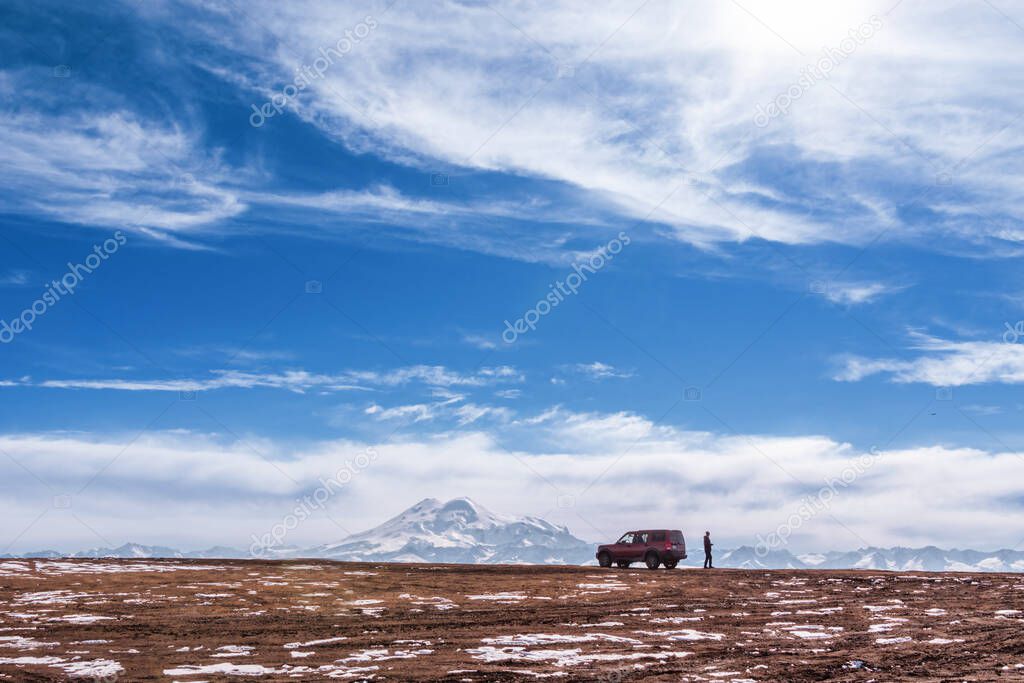 Vista del Monte Elbrus en otoño desde la meseta de Bermamyt, junto a las siluetas de un coche y ...