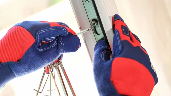 Builder repairs plastic window with hexagon with screwdriver indoors ...