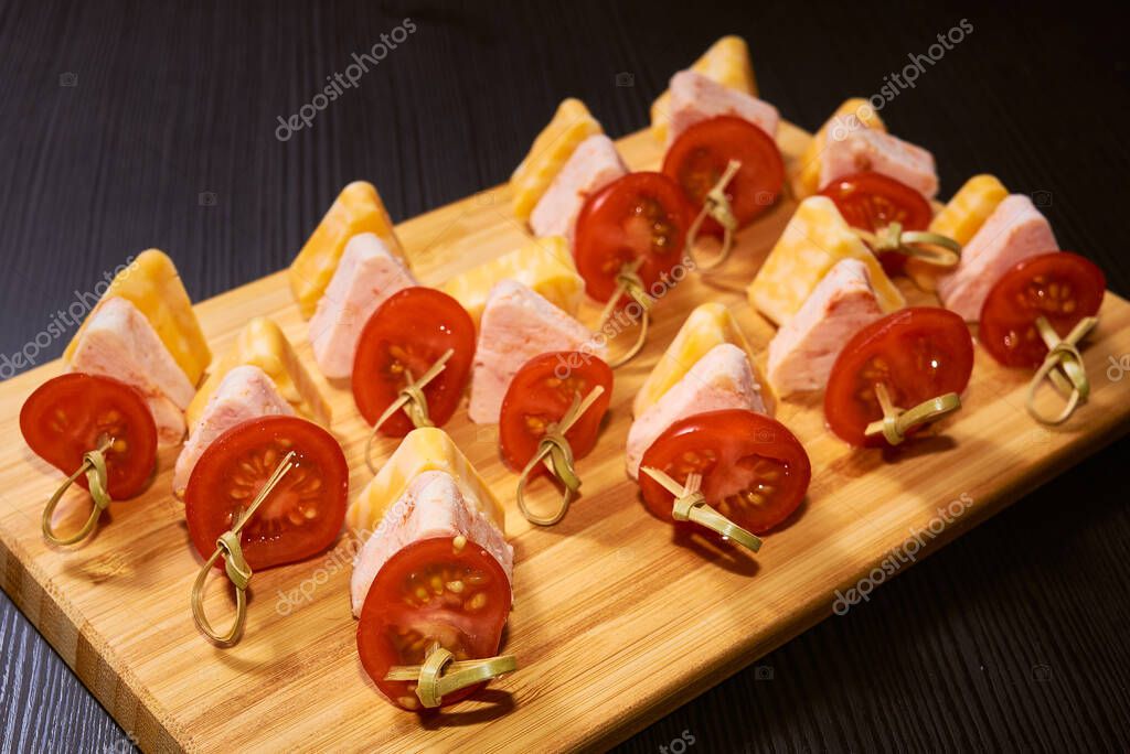Canapés en pinchos de bambú hechos de jamón casero, trozos de queso en ...