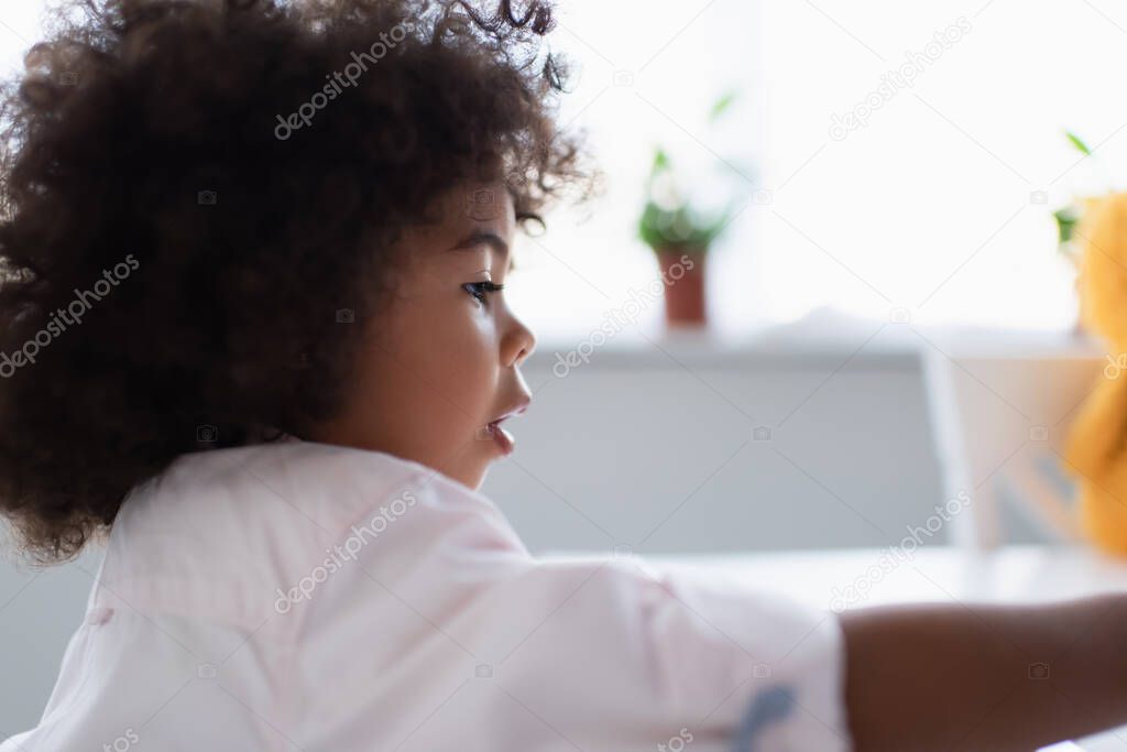 vista lateral de la chica americana africana rizada en casa, borrosa ...