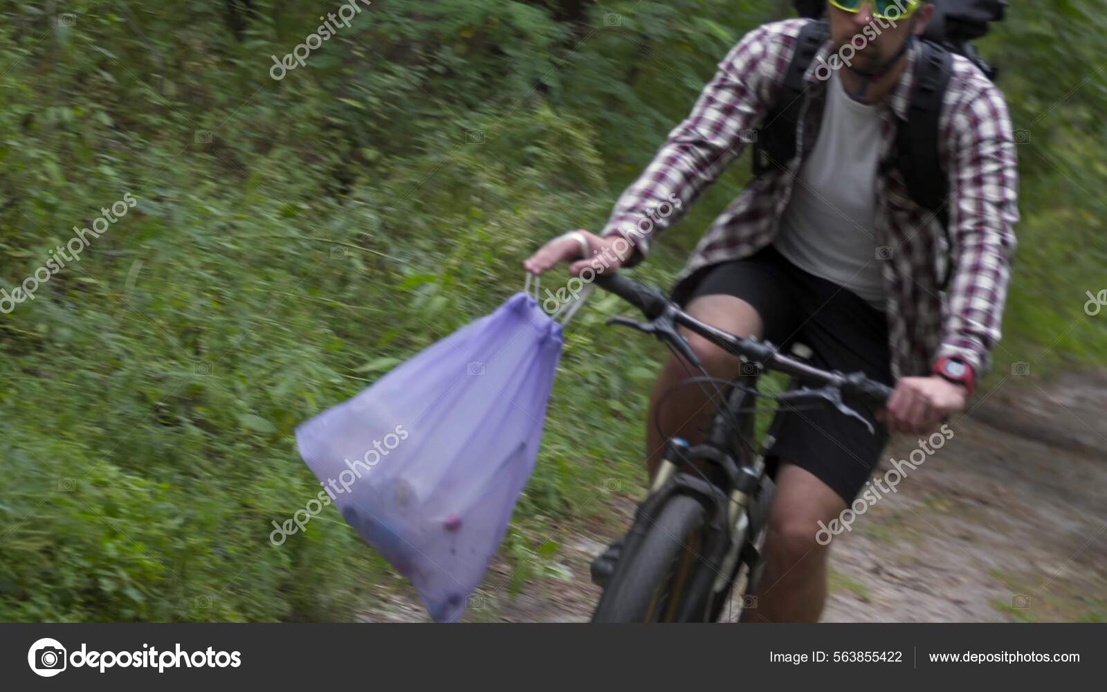 Pollution. Ecological problem. Male cyclist carry garbage bag on ...