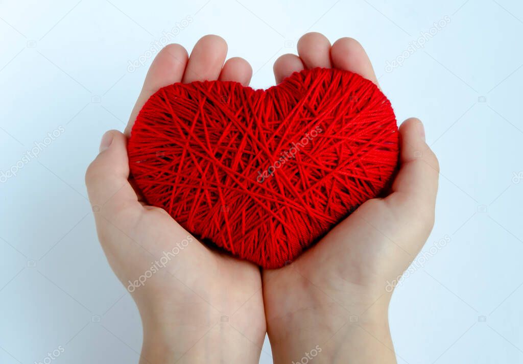 Un corazón hecho de hilos rojos en sus manos. El concepto de ...