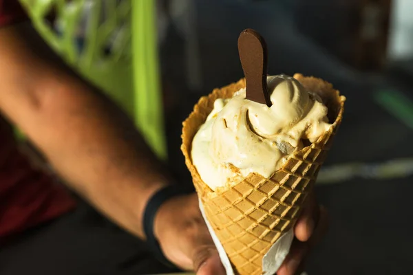 Mano sosteniendo un delicioso cono de helado cremoso en un día soleado ...