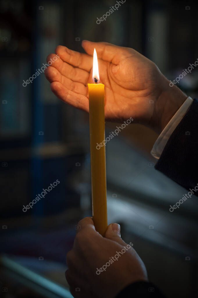 Primer plano de las manos del hombre religioso sosteniendo la vela ...