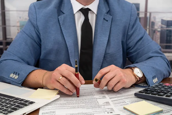 businessman man in a classic suit works with documents as tax forms of ...