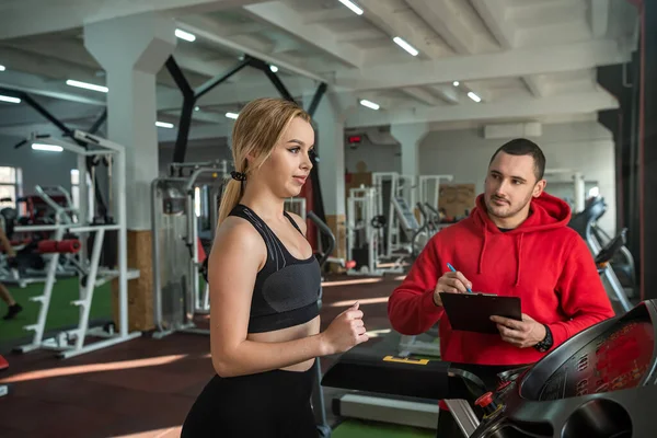 Female athlete with assistant personal trainer running on treadmills ...