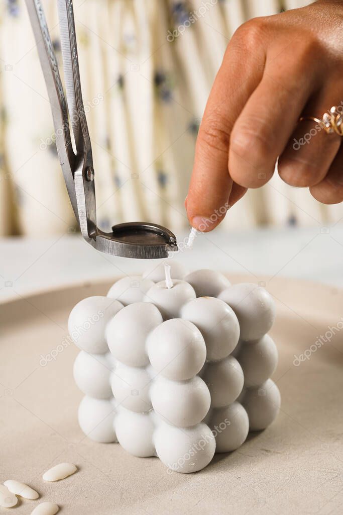 Manos femeninas cortando una mecha de una vela de burbuja gris en ...