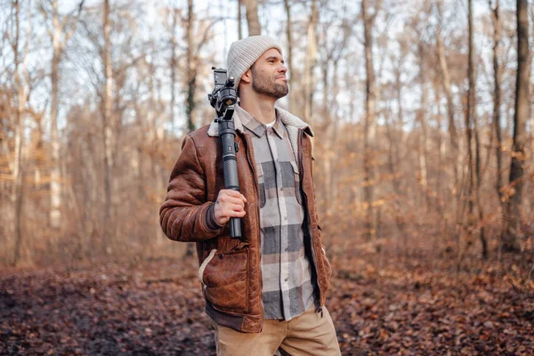 A portrait of a young white man posing in the woods dressed in autumn ...