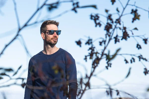 Young man staring at the distance seen through tree branches - Stock ...