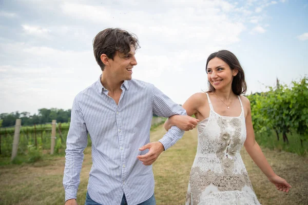 Beautiful young model couple walking in the vineyard looks into each ...