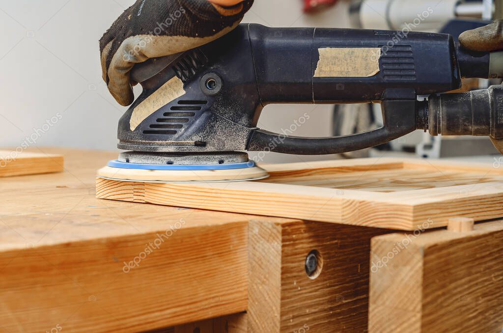 Lijando una tabla de madera con una lijadora eléctrica de mano 2024