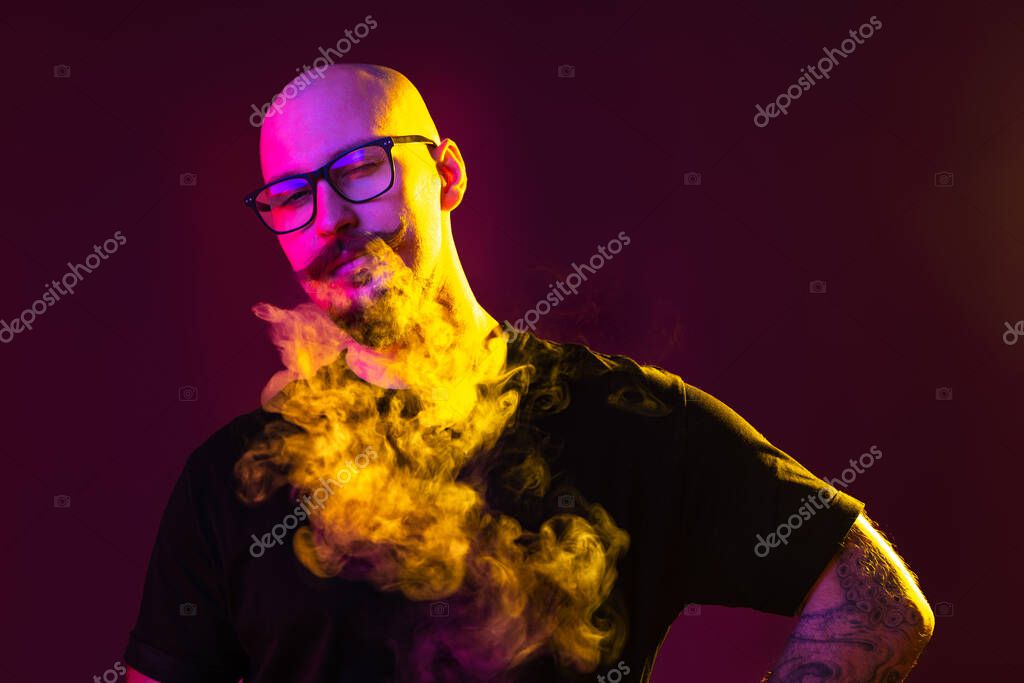 Retrato de un calvo guapo que fuma mientras sopla humo. filtros de ...