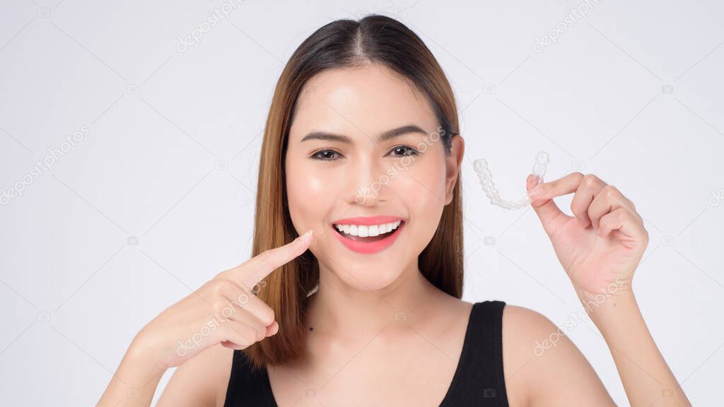 Joven mujer sonriente sosteniendo frenos invisalign en el estudio, la ...