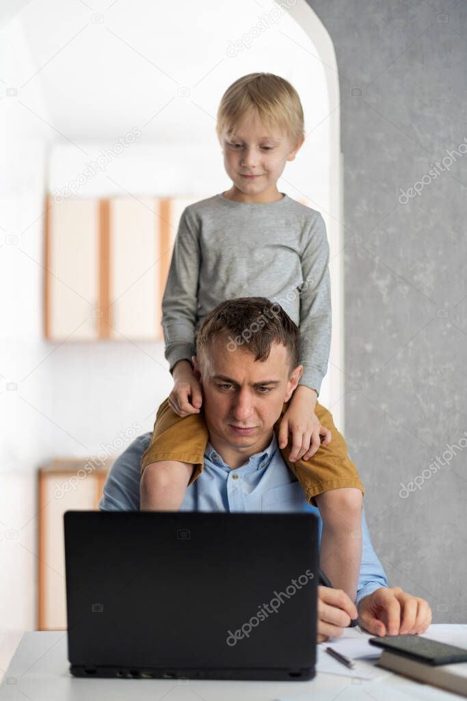 El padre joven trata de trabajar en casa con los niños. El hijo se ...