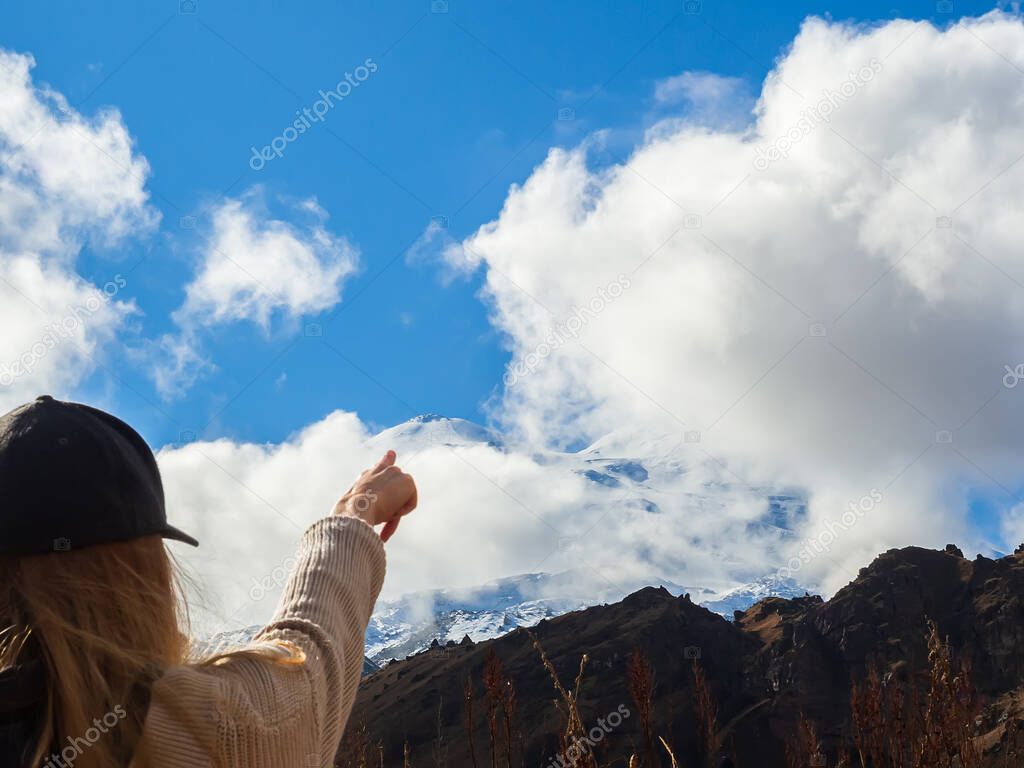 La niña señala con el dedo el pico blanco de Elbrus, visible a través de las nubes sobre el ...