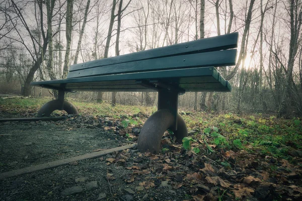 Wooden park bench over abandoned railroad tracks in a park in autumn ...