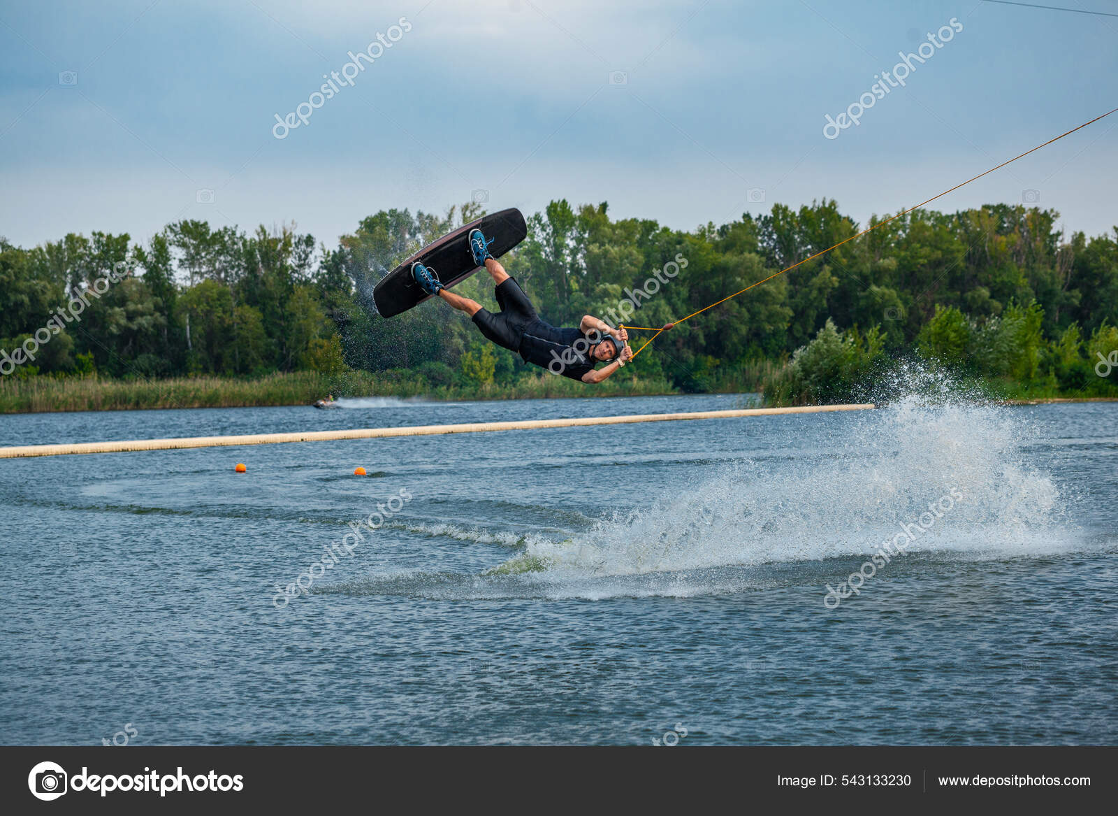 Experienced wakeboard rider jumping and spinning in air holding on to ...