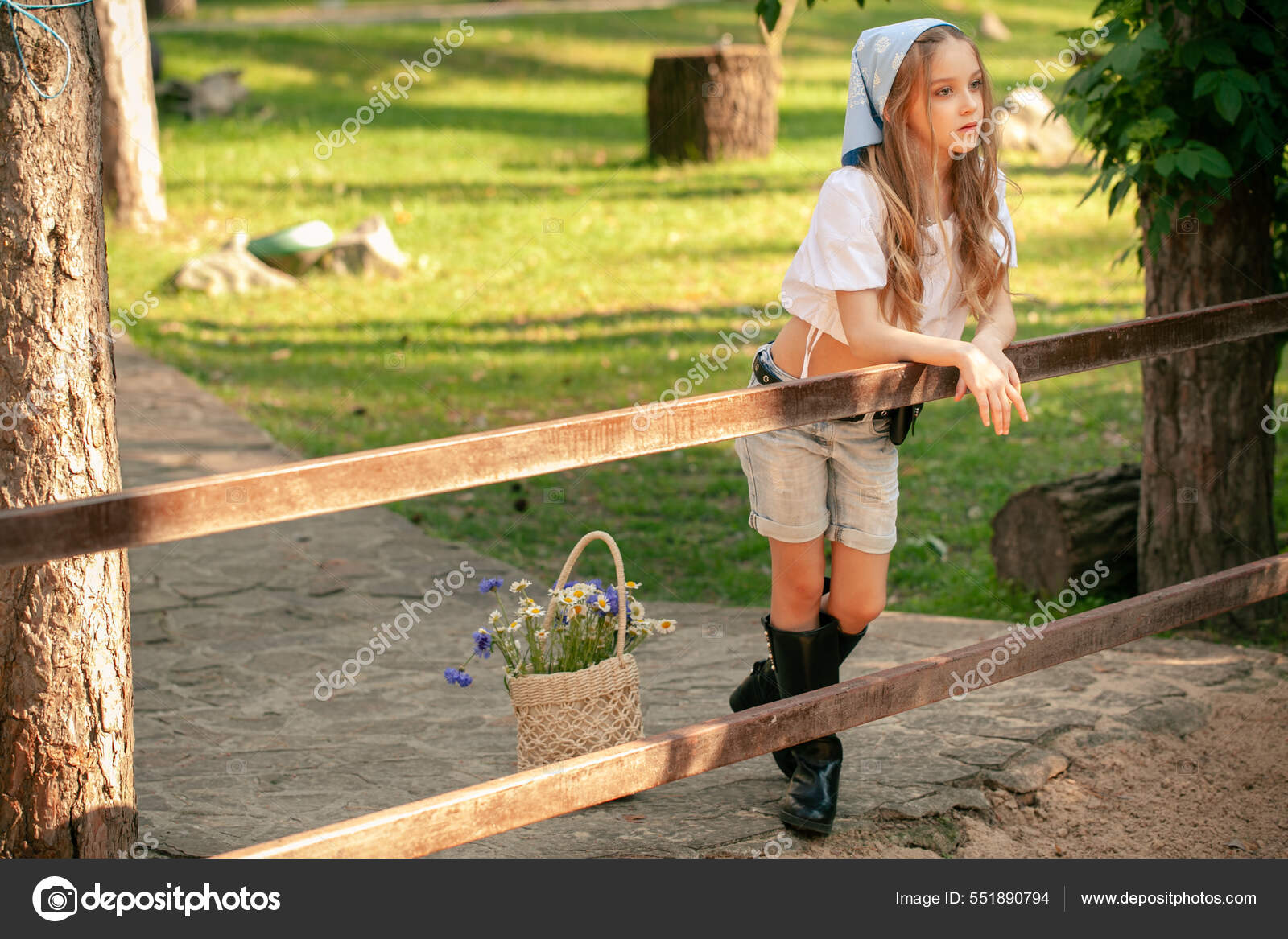 Teenage girl leaning on iron fence while walking in summer country park ...