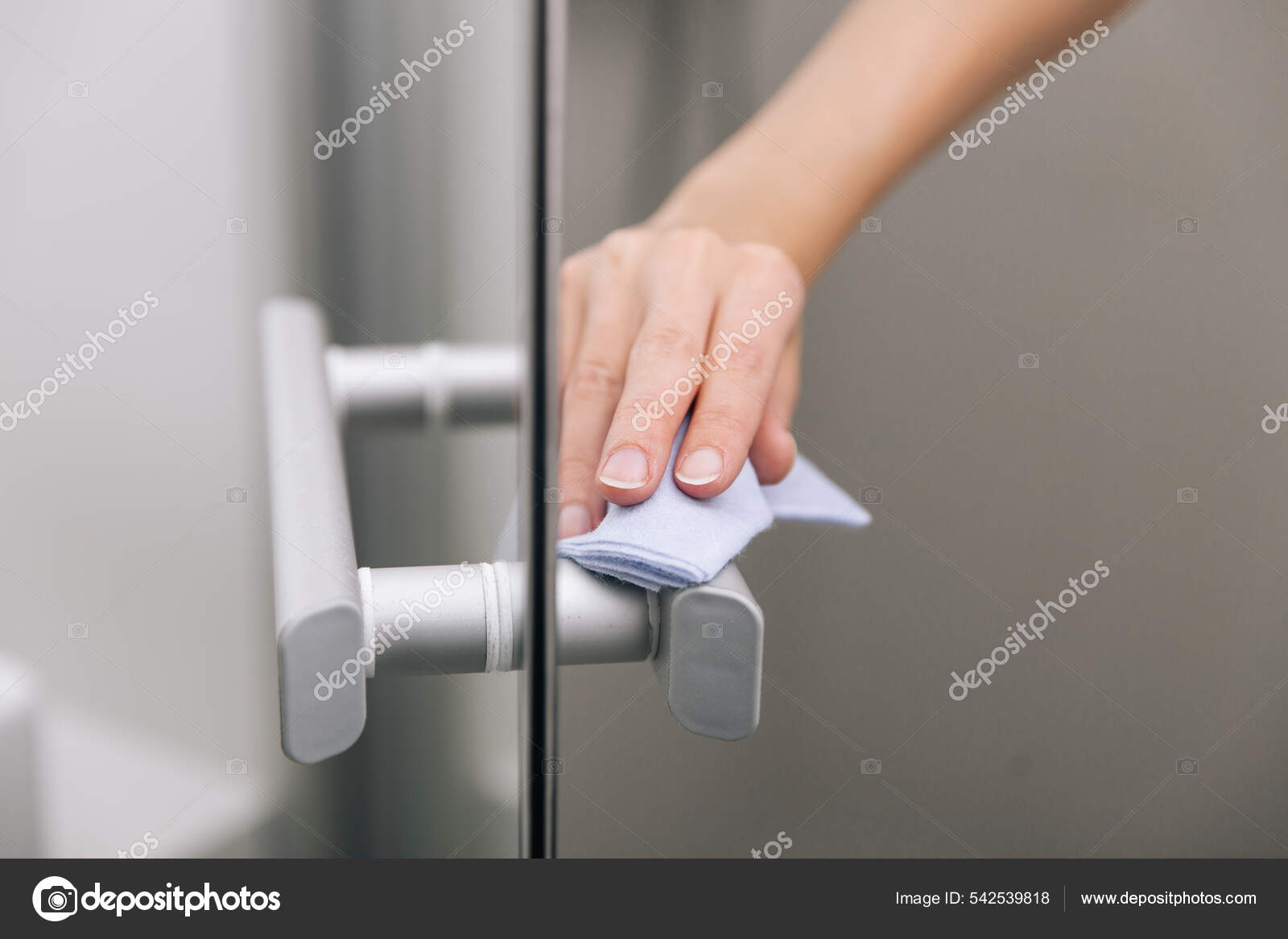 Cleaning glass door handles with an antiseptic wet wipe. Woman hand ...