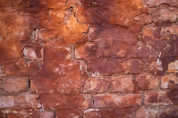 The texture of a red concrete wall with cracks and scratches can be ...