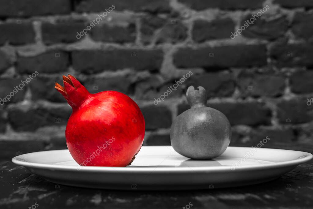 Granada roja entera y granada blanca y negra en un plato blanco grande ...