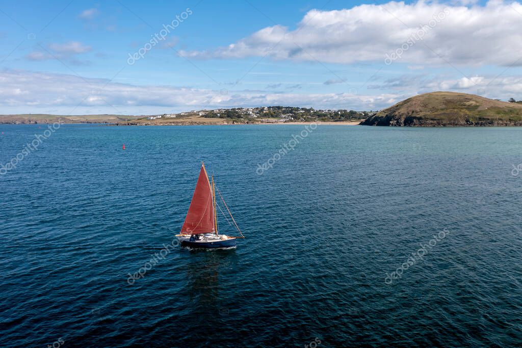 Un velero a la antigua usanza con una vela roja flotando en el océano ...