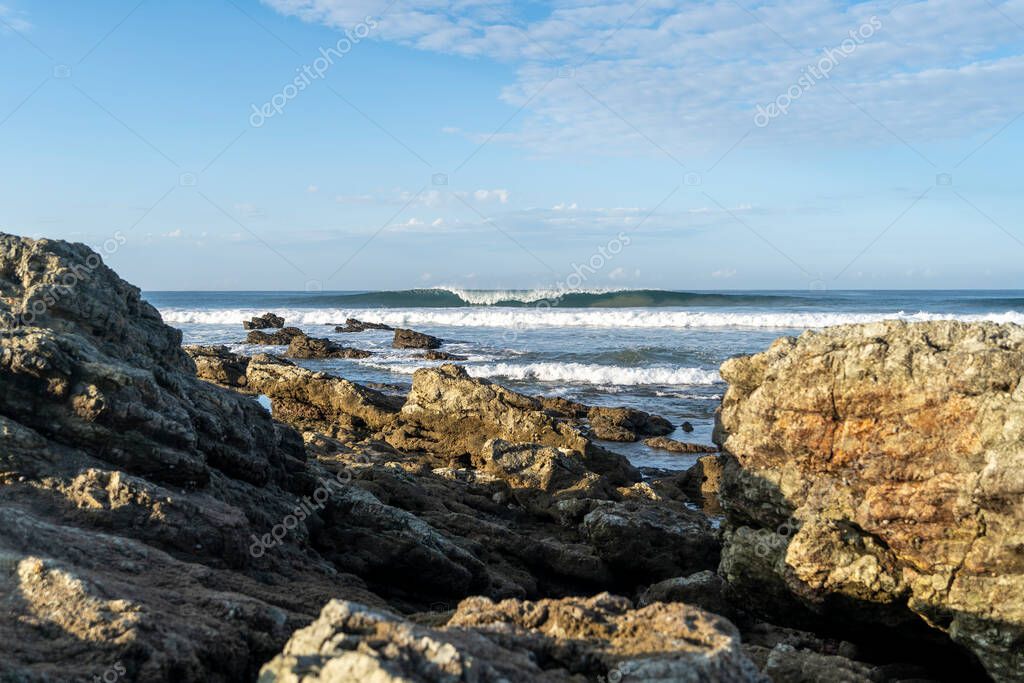 Una ola perfecta rompiendo detrás de las rocas. Surf en Costa Rica. 2024