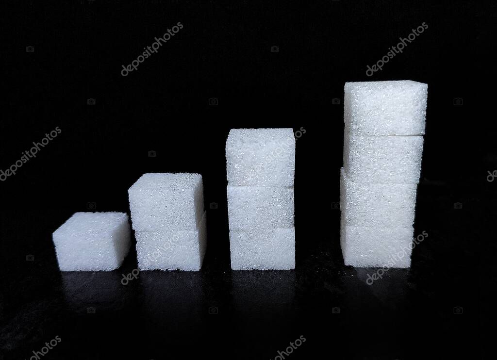 Cubos de azúcar apilados uno encima del otro en columnas, fondo negro. 2022