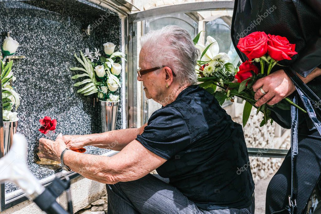 anciana poniendo flores en la tumba de su difunto esposo en el ...