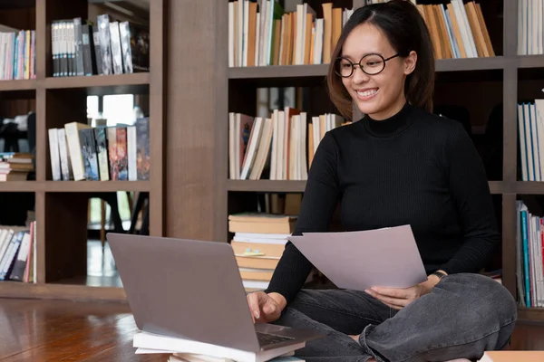 University library: beautiful asian woman uses laptop, Study for class assignment. focused ...