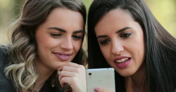 Authentic friends laughing together outdoors checking cellphone Close ...
