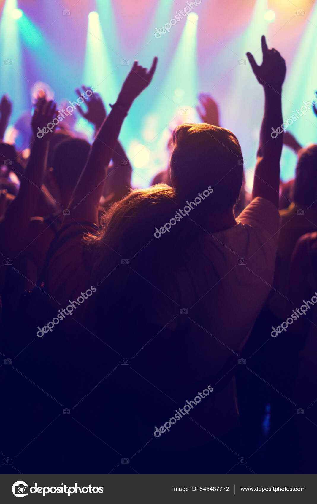 A crowd of people watching a band play on stage at a nightclub. This ...