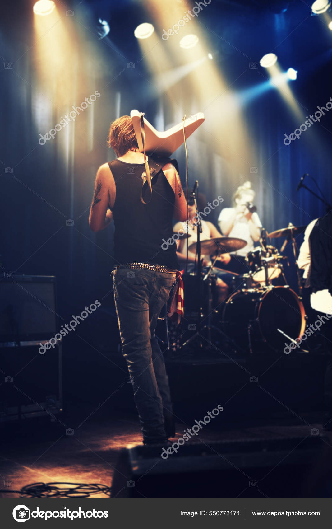 Rocking out. A guitarist on stage with his band beneath strobe lights ...