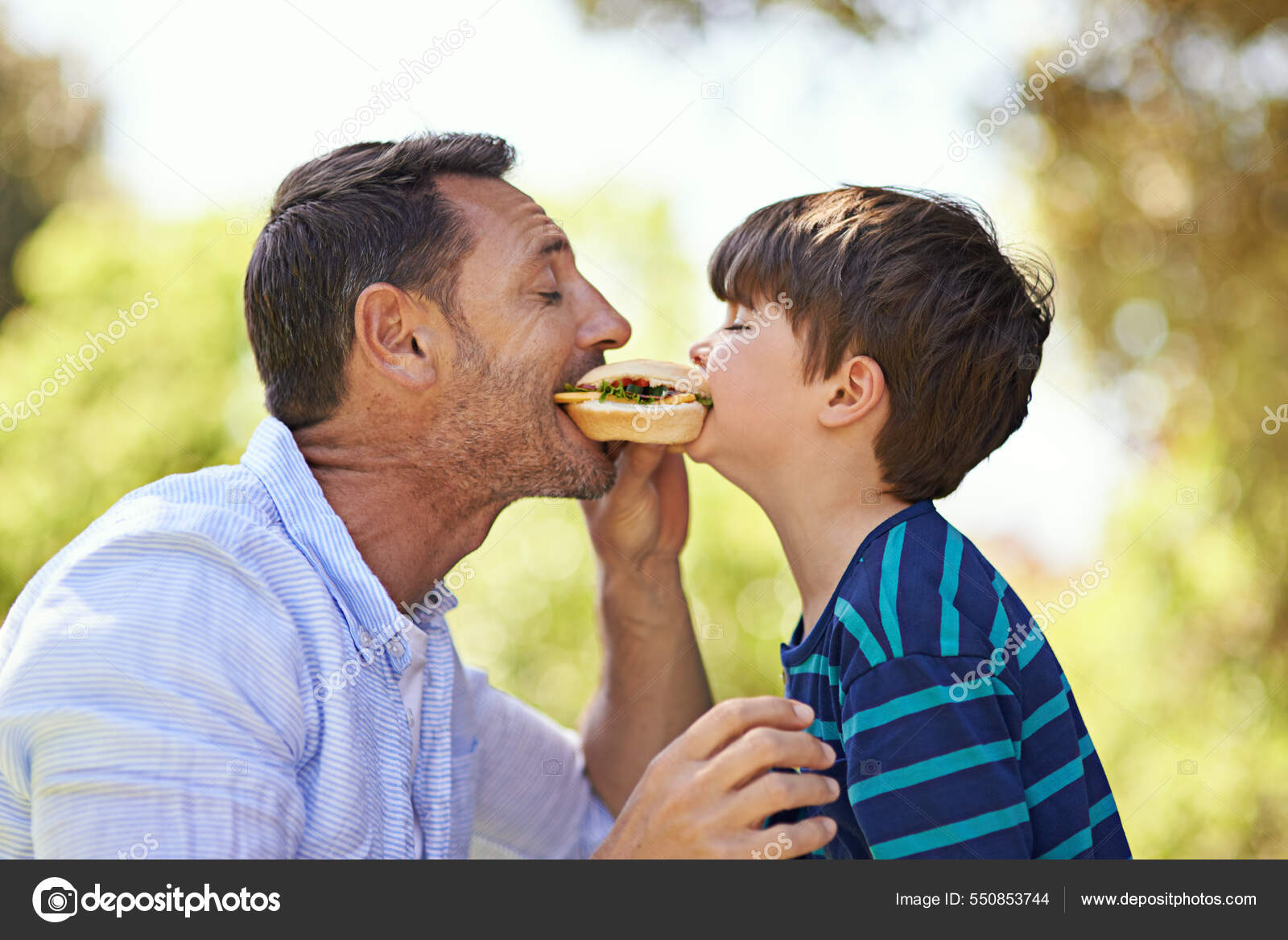 Whos got the biggest bite. Shot of a father and son biting into a ...